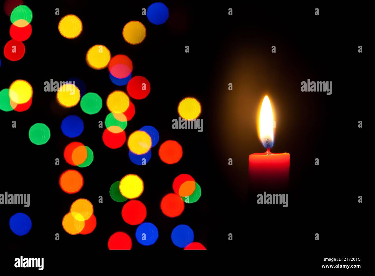 detail of red candle with defocused colorful lights on black background ...