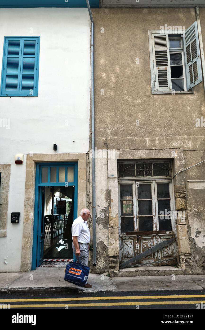 Man walking past a newly refurbished building next to a derelict ...