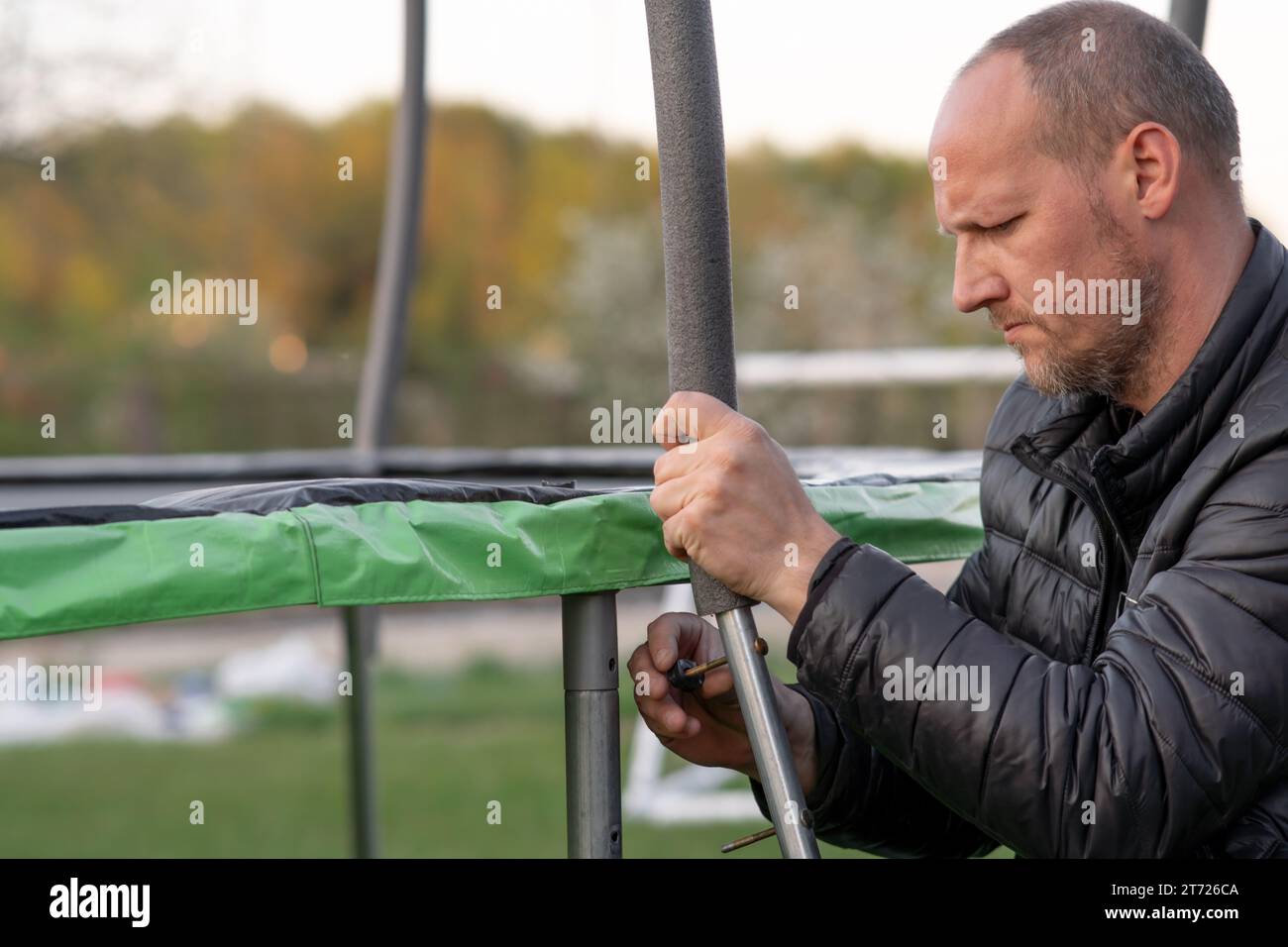 Middle aged human with furrowed eyebrows fastening metal posts to ...