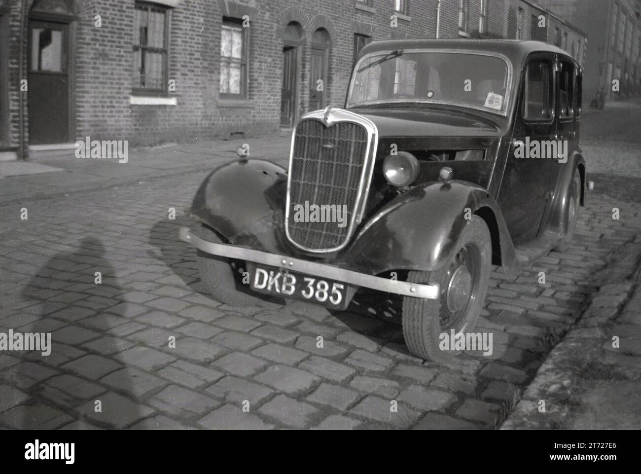 1950s, historical, a motor car of the era parked on a cobbled street of ...
