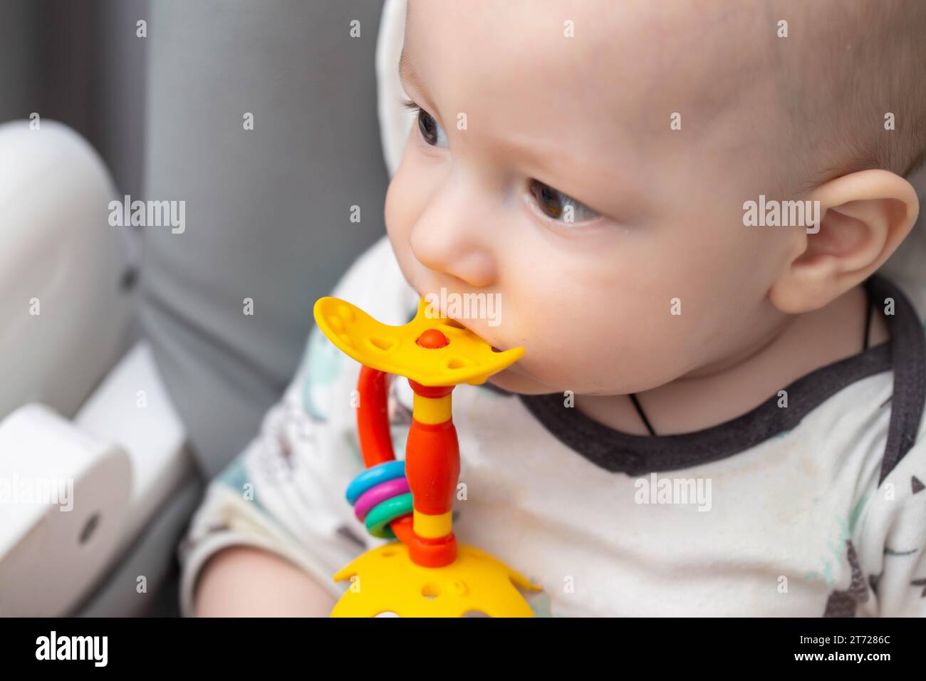 Portrait of a child who bites a multi-colored toy massager for teething ...