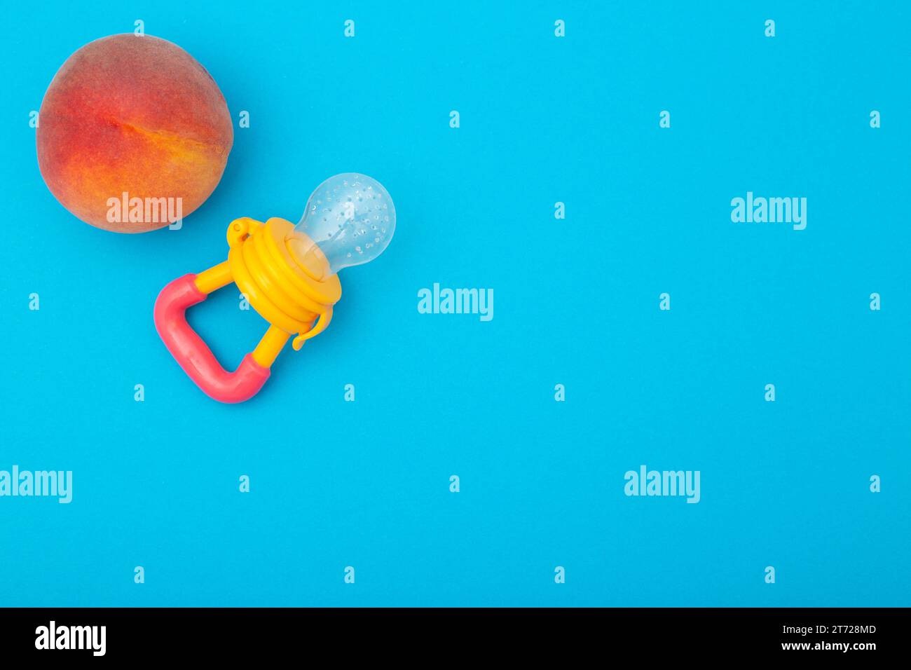 Peach with baby nibbler on a blue background. Concept of chewing reflex ...
