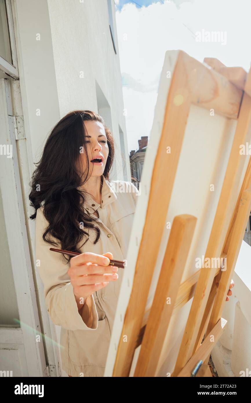 a female artist stands at an easel on a balcony Stock Photo - Alamy