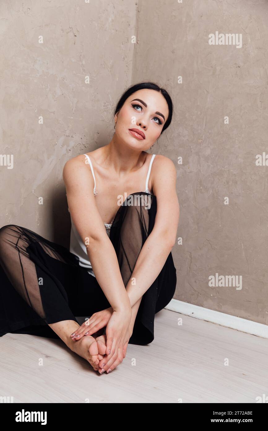 a brooding woman in black pants sits in a corner Stock Photo - Alamy
