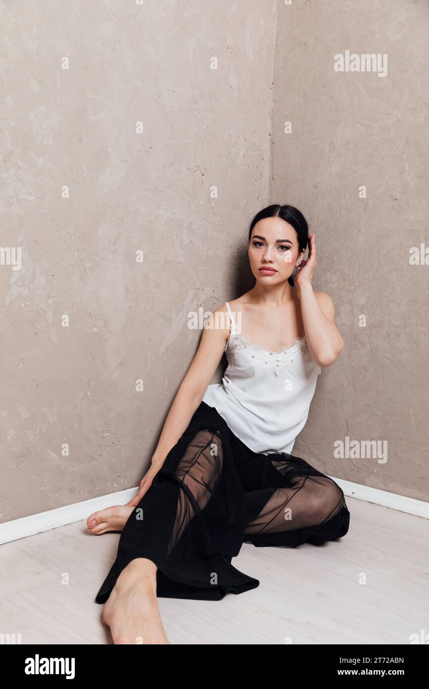 a brooding woman in black pants sits in a corner Stock Photo - Alamy