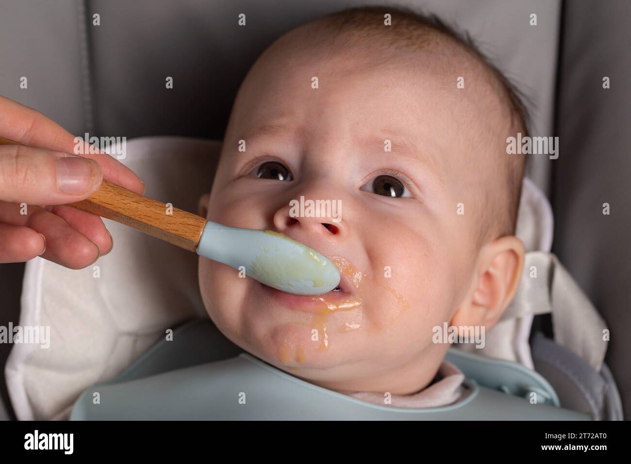 A 6-month-old baby tries porridge for the first time. Feeding babies ...