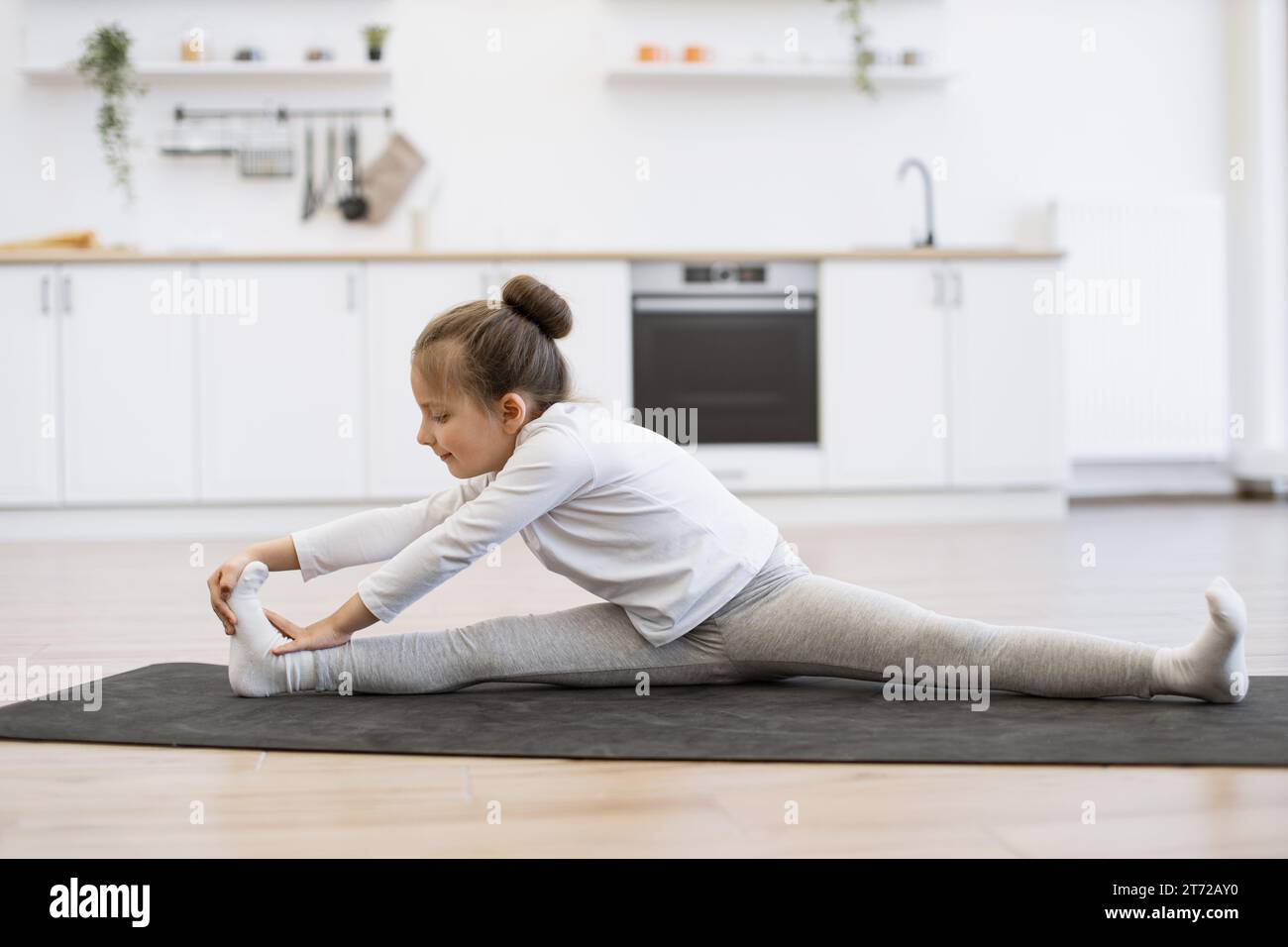 Girl in white sports wear makes stretching training doing splits ...