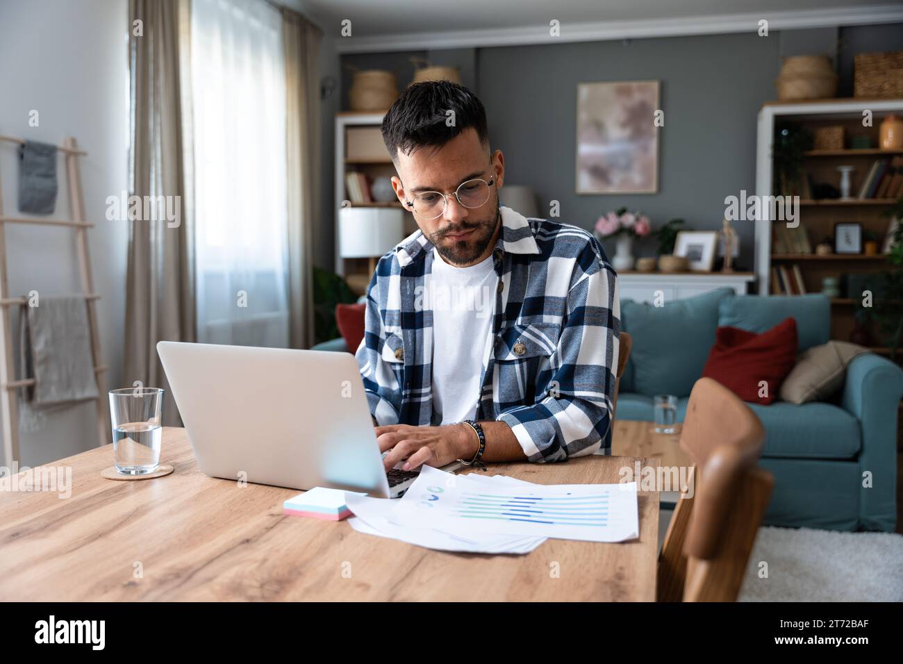 Young business man working at home with laptop and papers on desk ...