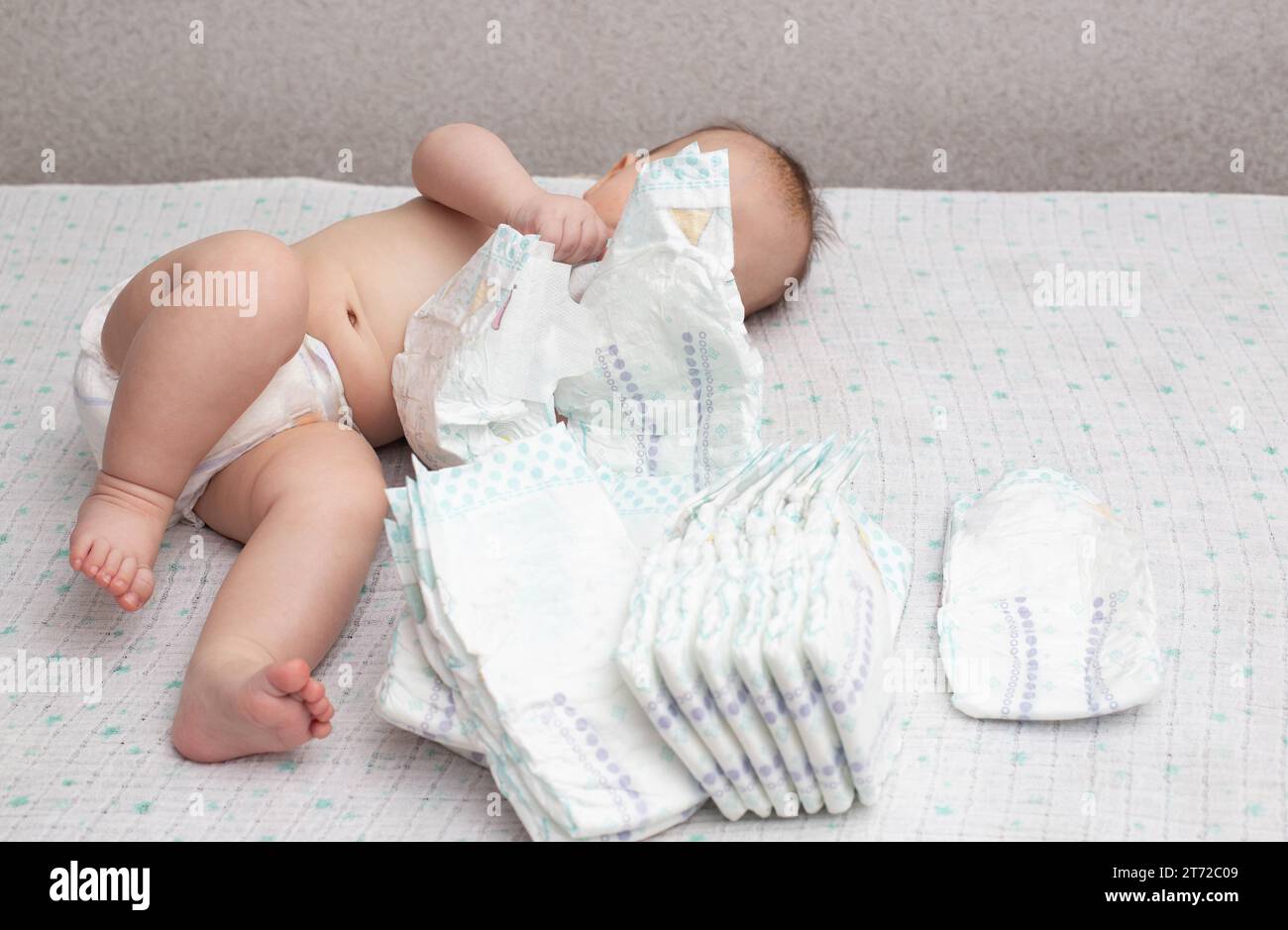 A little baby boy in a diaper lies on a white background and plays with ...
