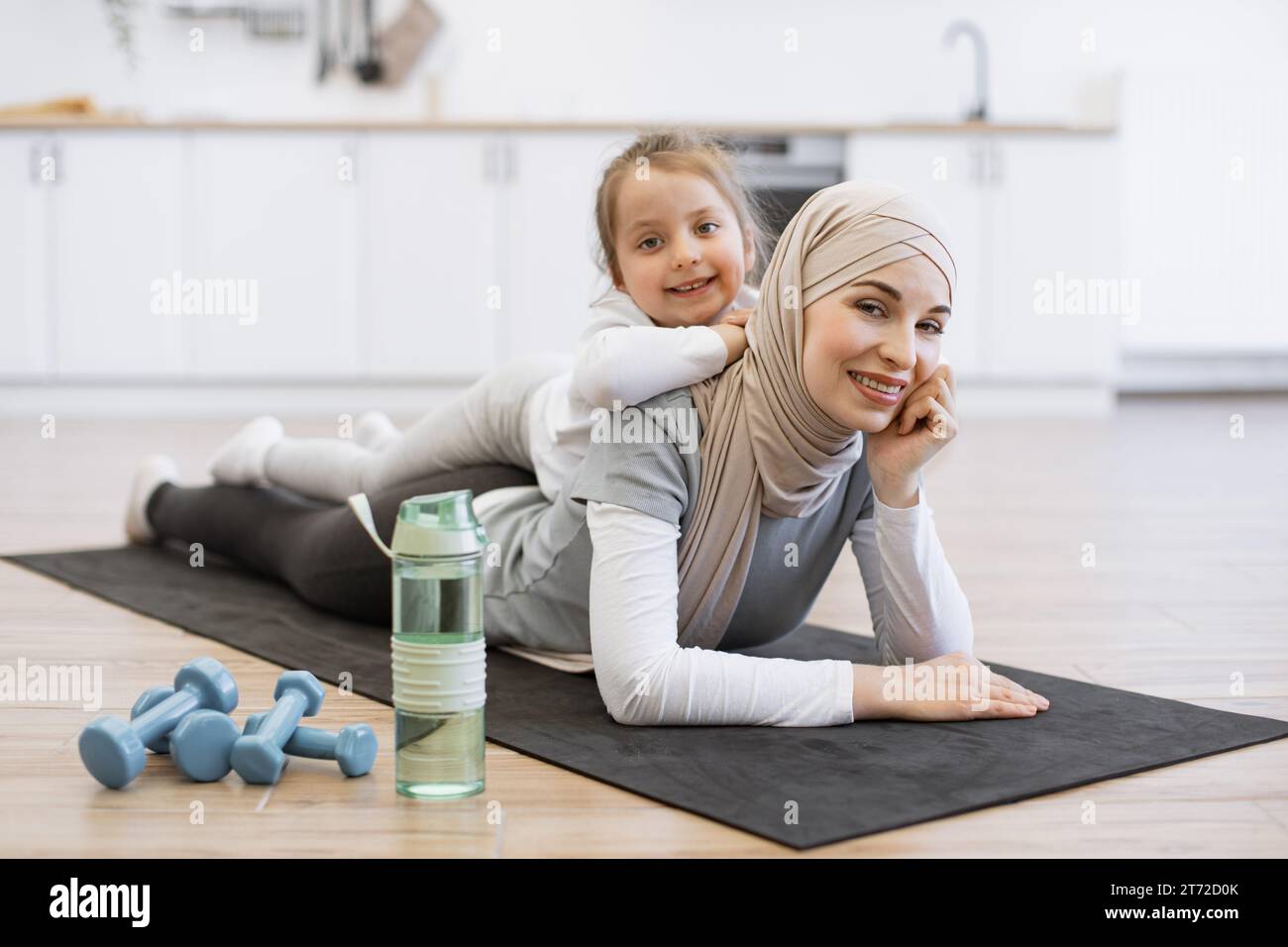 Muslim female in hijab relaxing with cute daughter after fitness ...