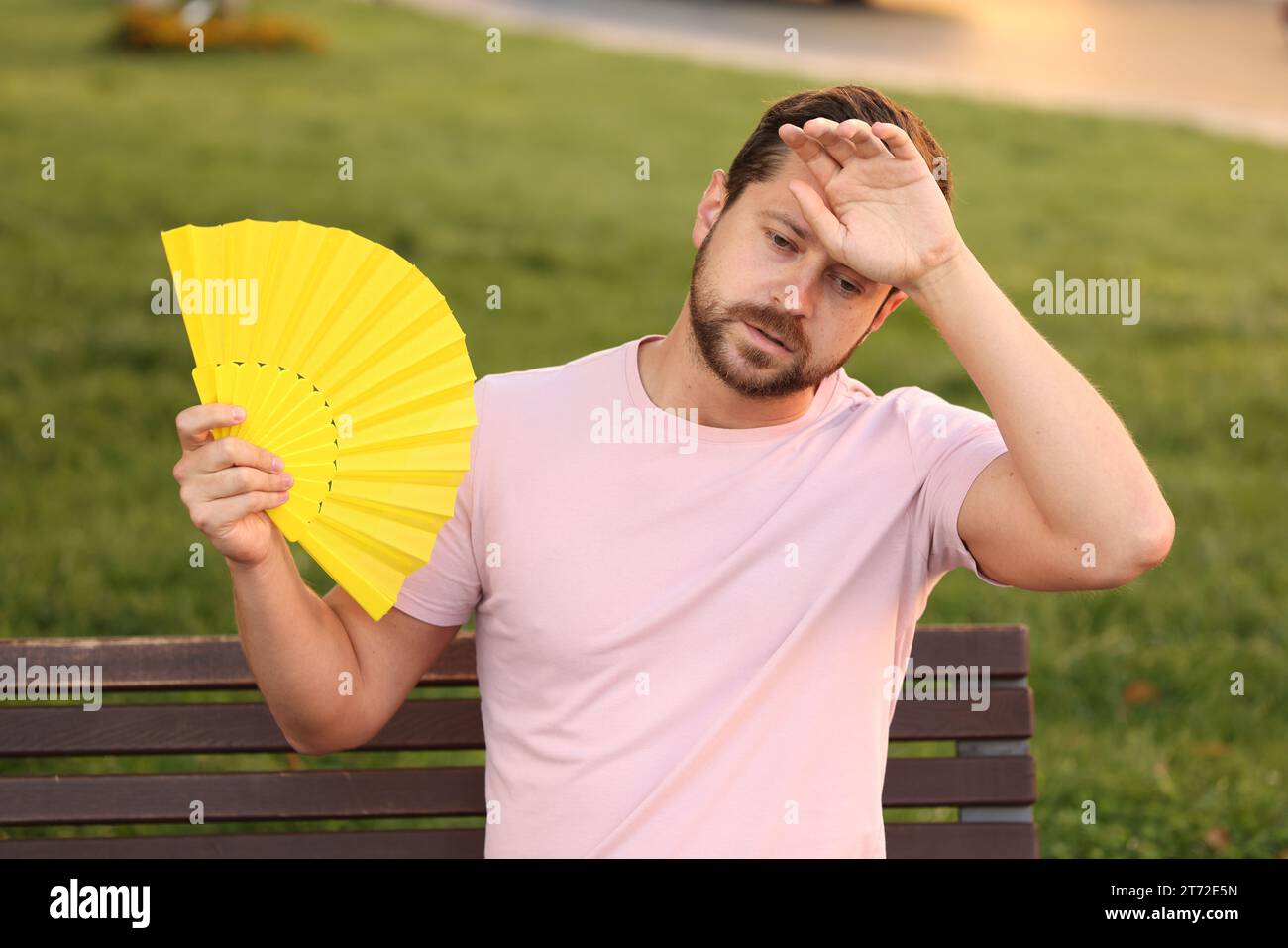 Man with hand fan suffering from heat outdoors Stock Photo - Alamy