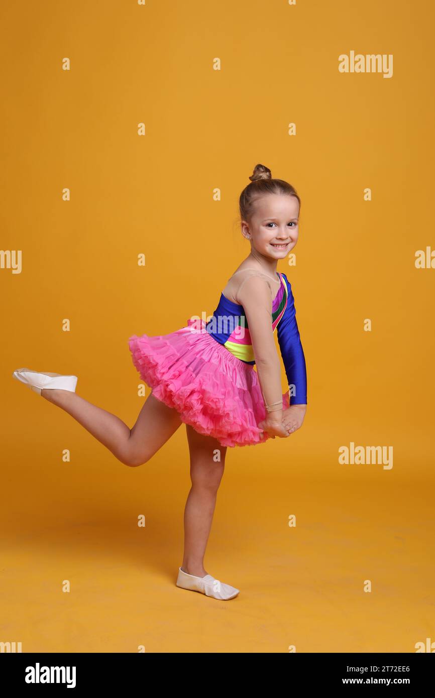 Cute little girl in costume dancing on orange background Stock Photo ...