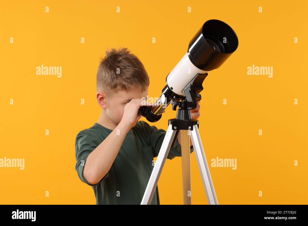Little boy looking at stars through telescope on orange background ...