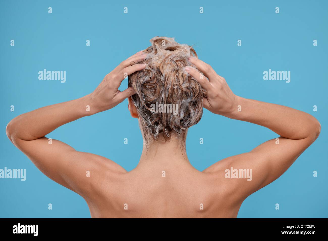 Woman washing hair on light blue background, back view Stock Photo - Alamy