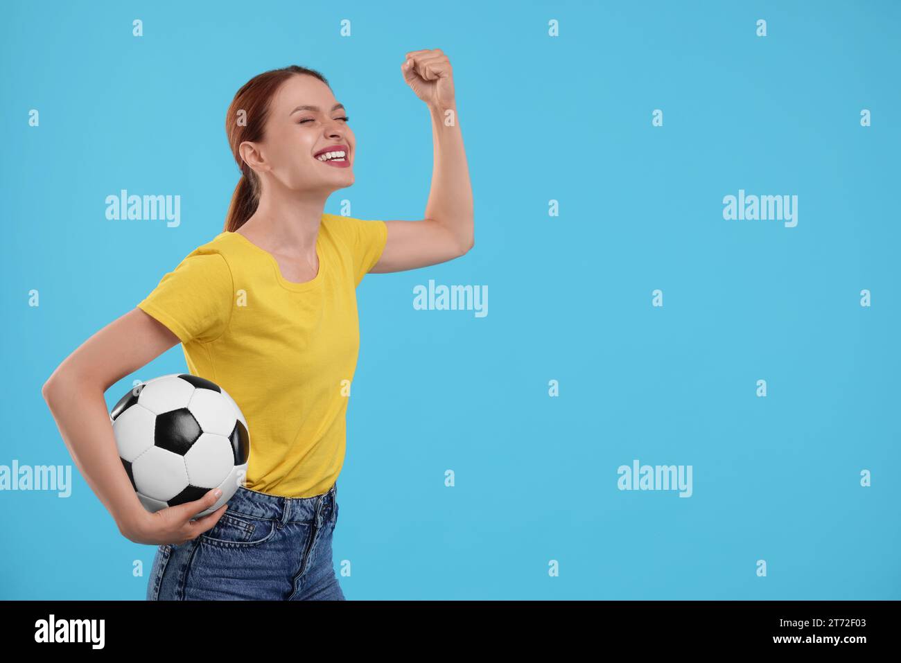 Emotional fan holding football ball and celebrating on light blue ...