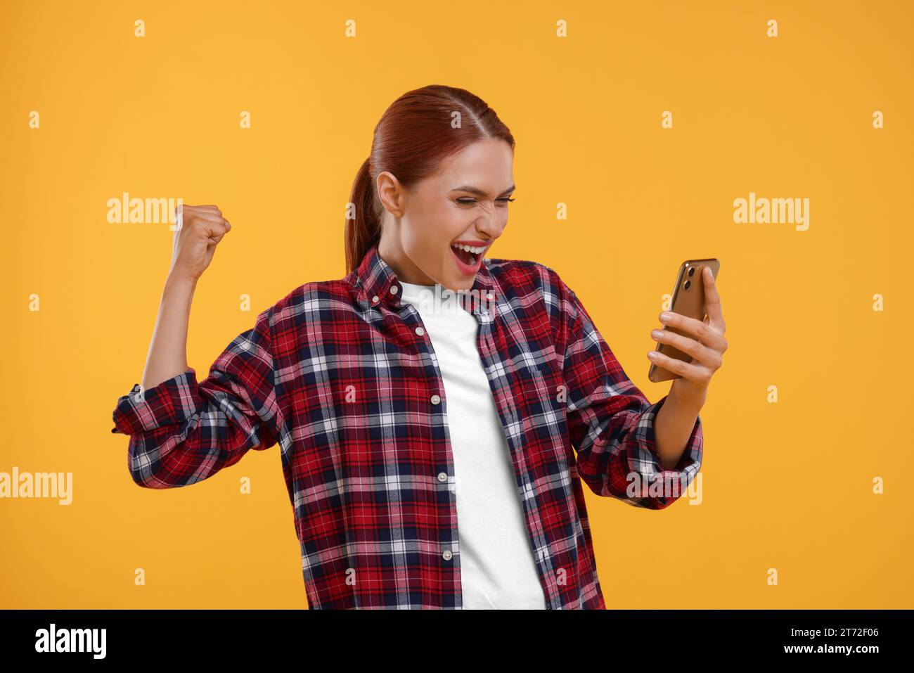 Emotional fan looking into smartphone and celebrating on yellow ...