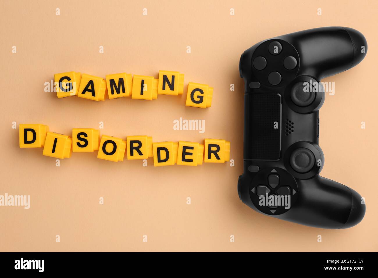 Phrase Gaming Disorder made of yellow cubes and gamepad on beige ...