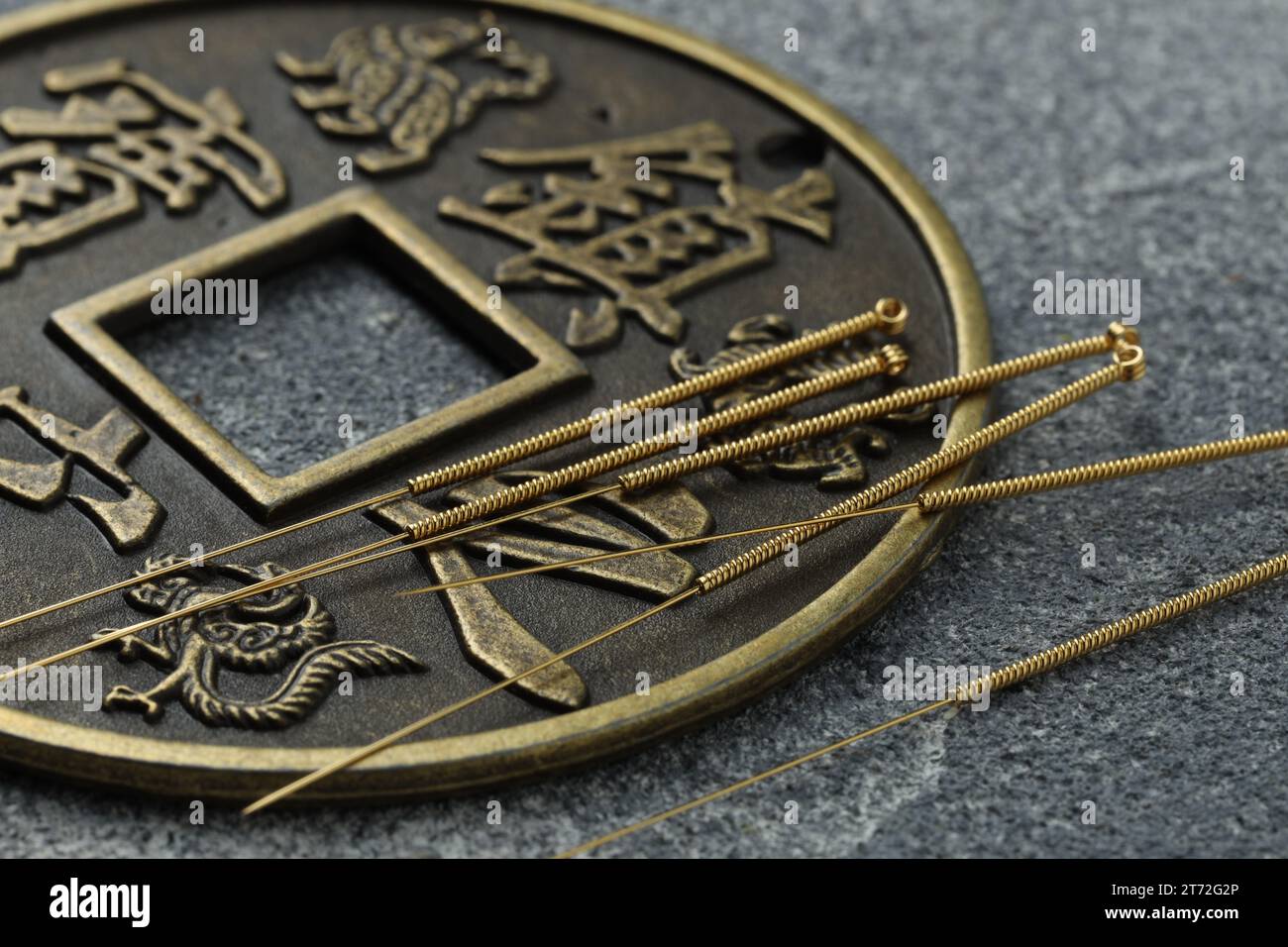 Acupuncture needles and ancient coin on grey textured table, closeup ...