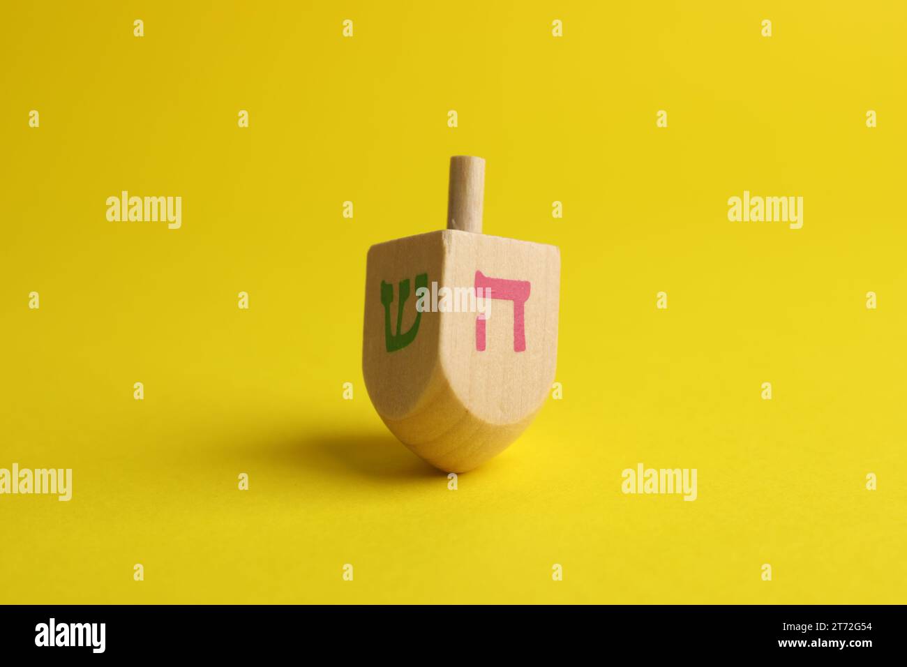 Wooden dreidel on yellow background. Traditional Hanukkah game Stock ...