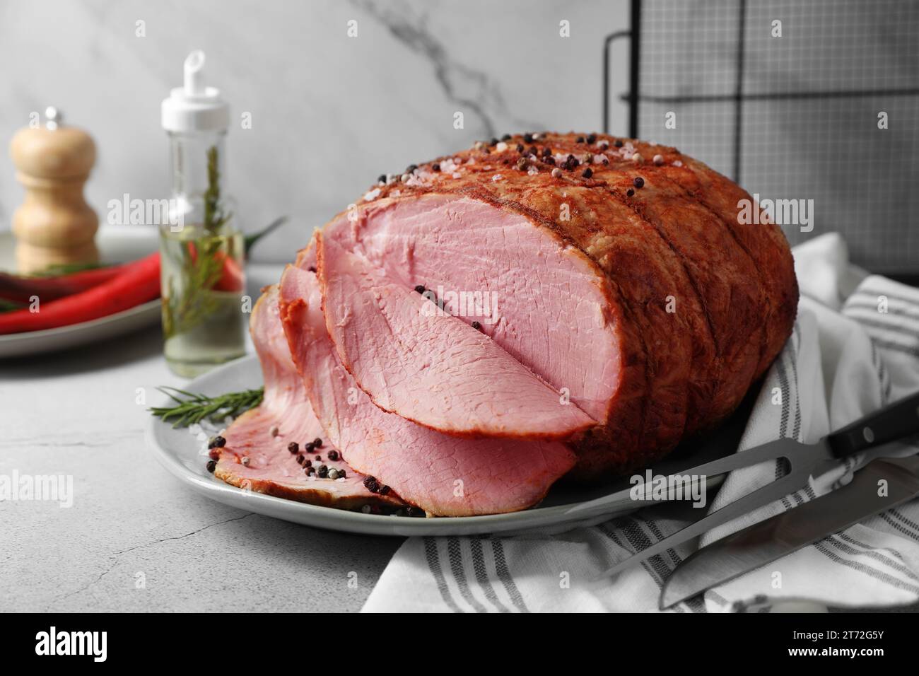 Delicious baked ham, carving fork and knife on light grey table Stock ...