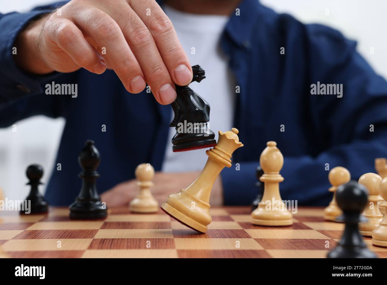 Man moving knight on chessboard indoors, closeup Stock Photo - Alamy