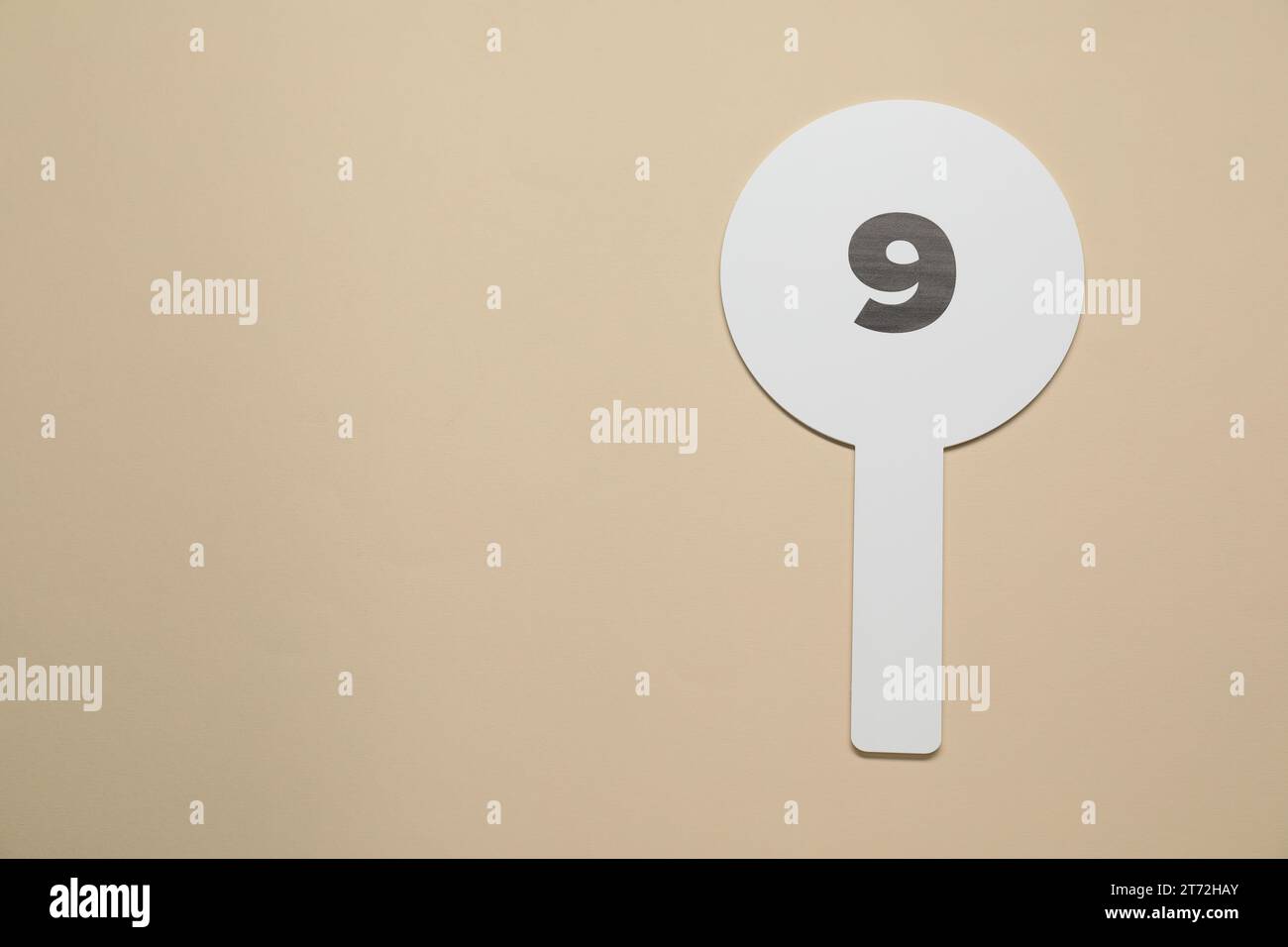 Auction paddle with number 9 on beige background, top view. Space for ...