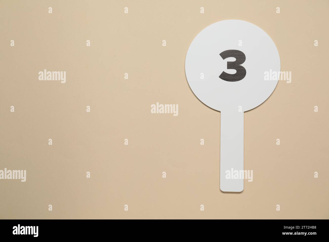 Auction paddle with number 3 on beige background, top view. Space for ...