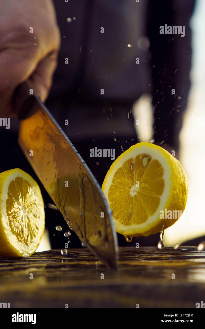 Adult man cutting lemon in half with knife. Human with knife in hand ...