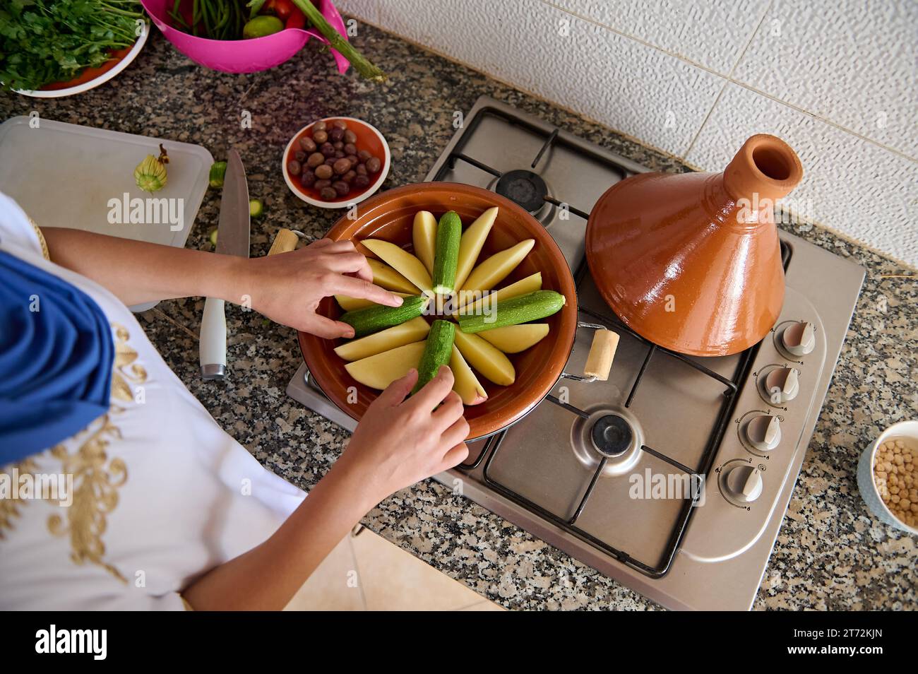 View from above Muslin housewife with head covered in hijab, putting ...