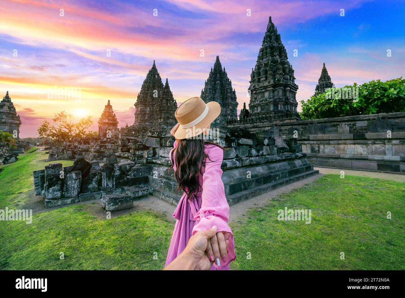 Women tourists holding man's hand and leading him to Prambanan Temple ...