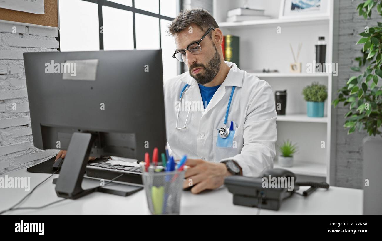 Bearded young hispanic man doctor hard at work, using his computer ...
