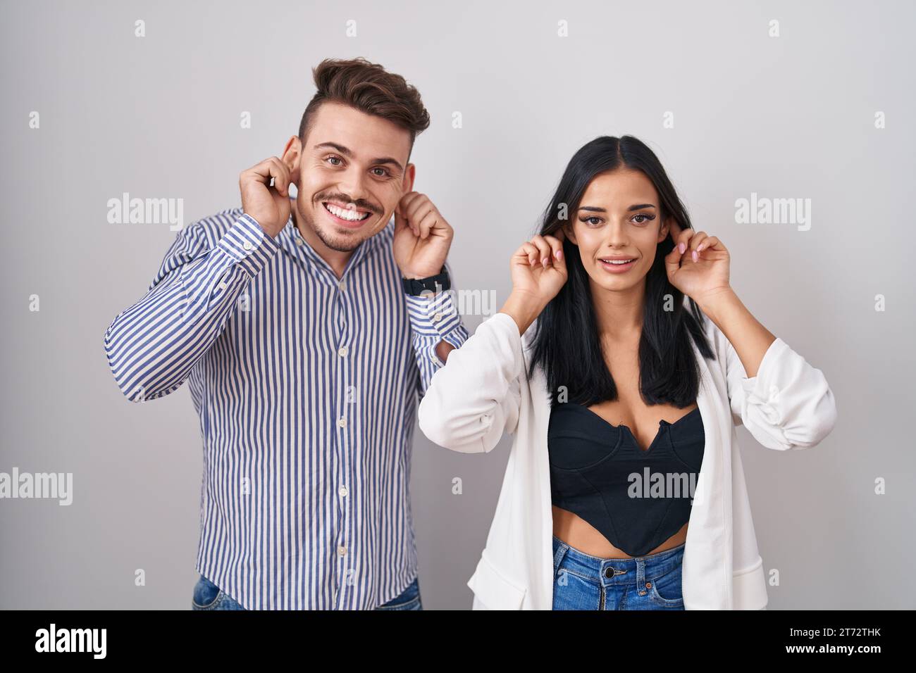 Young hispanic couple standing over white background smiling pulling ...