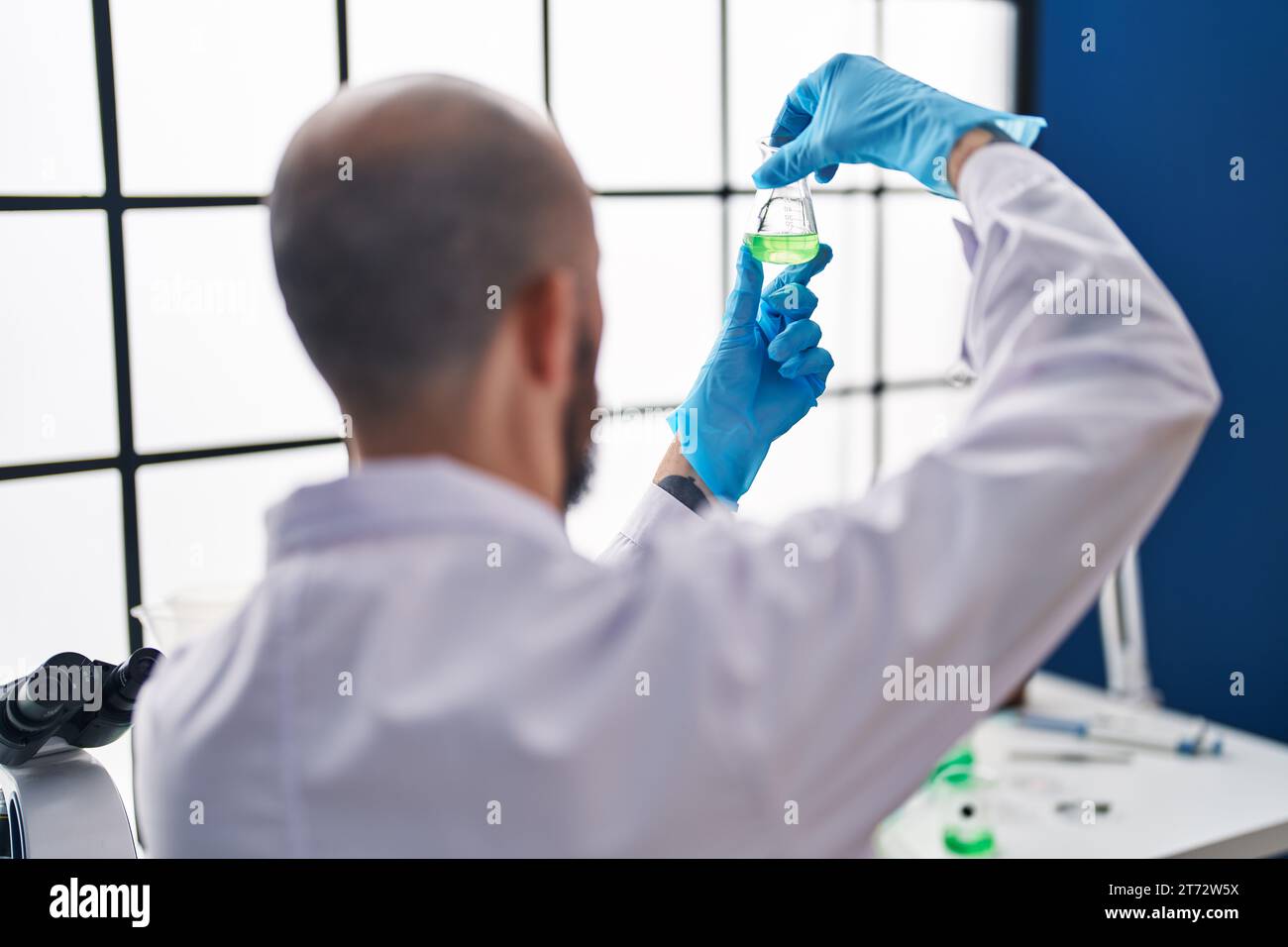 Young bald man scientist holding test tube at laboratory Stock Photo ...