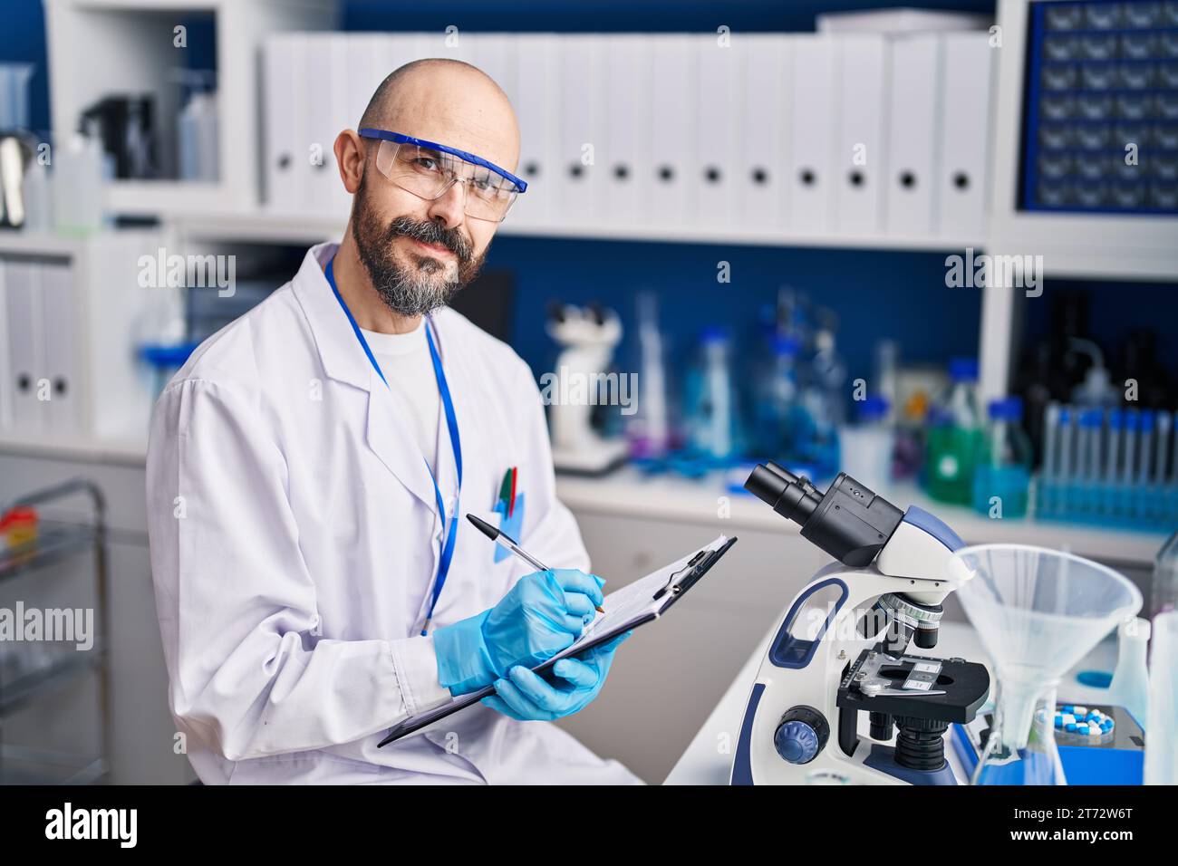 Young bald man scientist writing report working at laboratory Stock ...