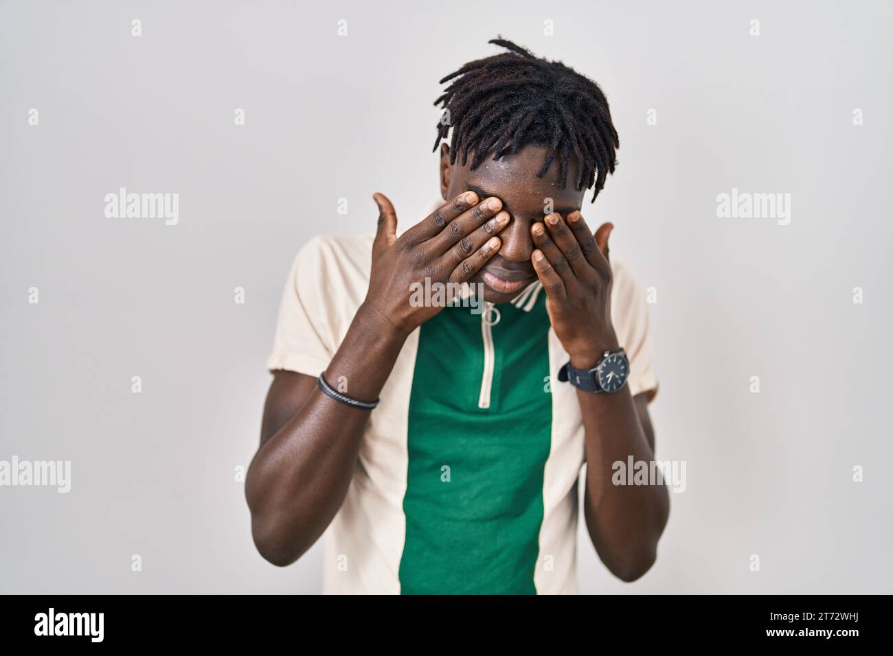 African man with dreadlocks standing over isolated background rubbing ...
