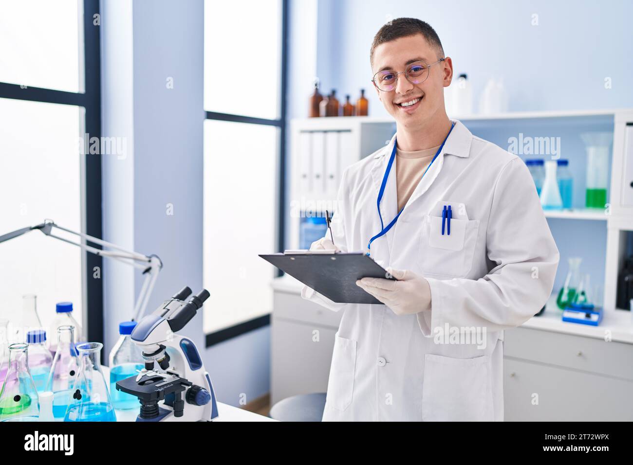 Young hispanic man scientist writing report working at laboratory Stock ...