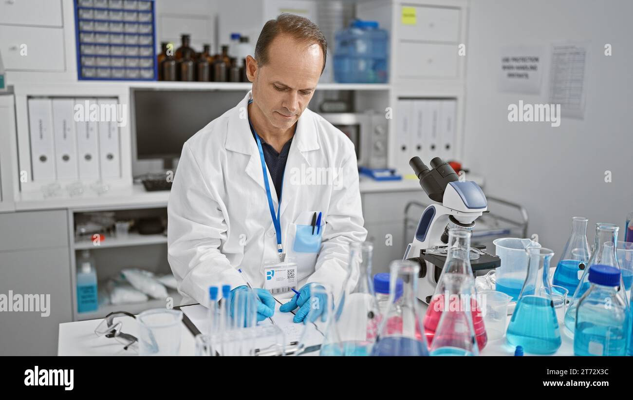 Serious middle age hispanic man scientist diligently writing ...