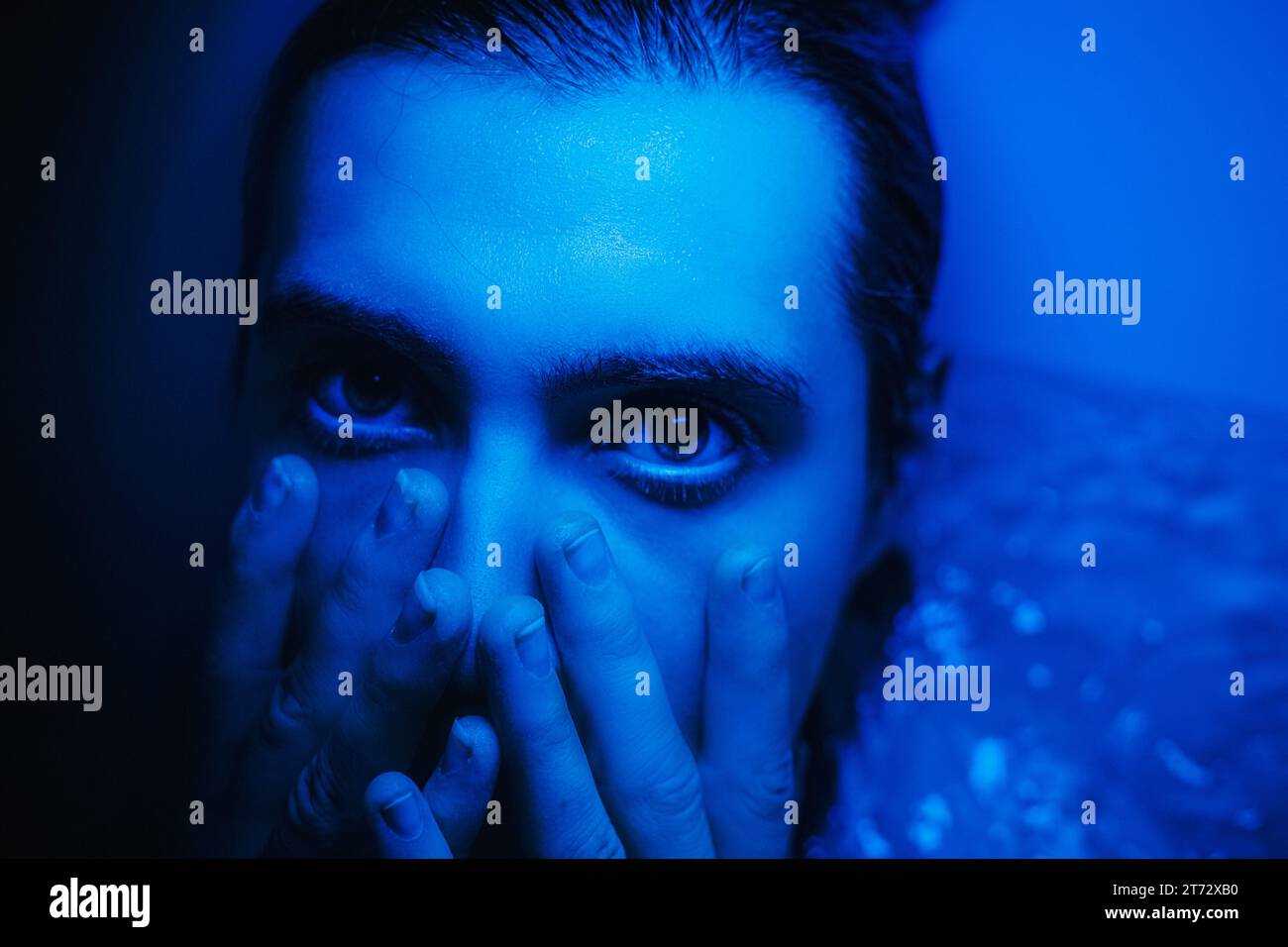 Portrait of a beautiful sad man who touches his face with his hands and ...