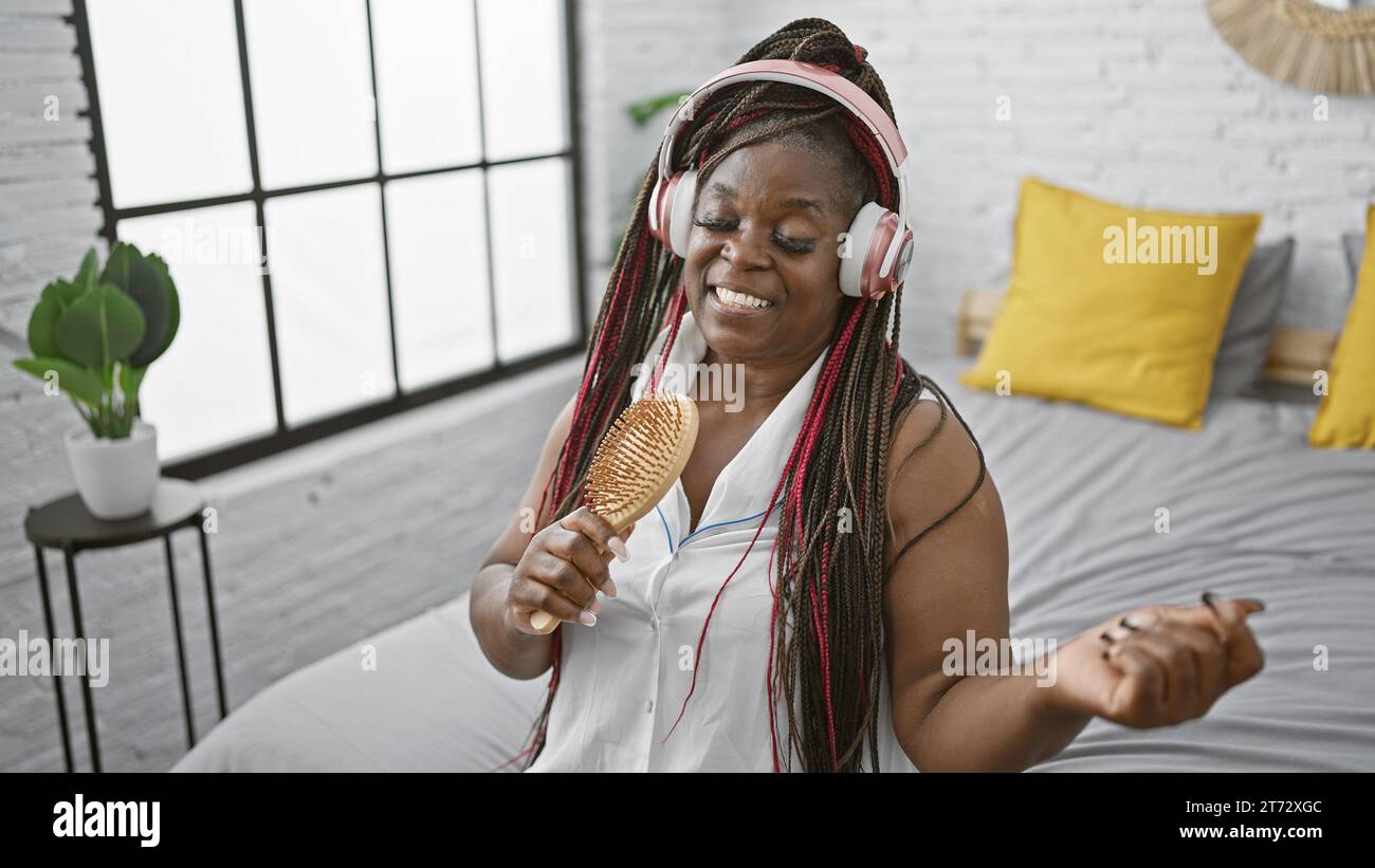 Joyful african american woman having fun singing a song with a brush as ...