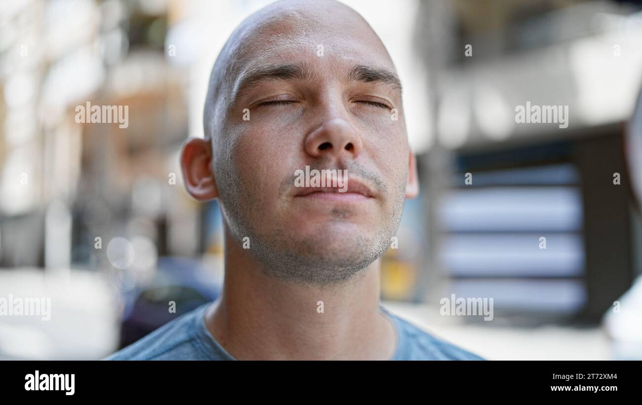 Young hispanic man standing with serious expression and closed eyes at ...