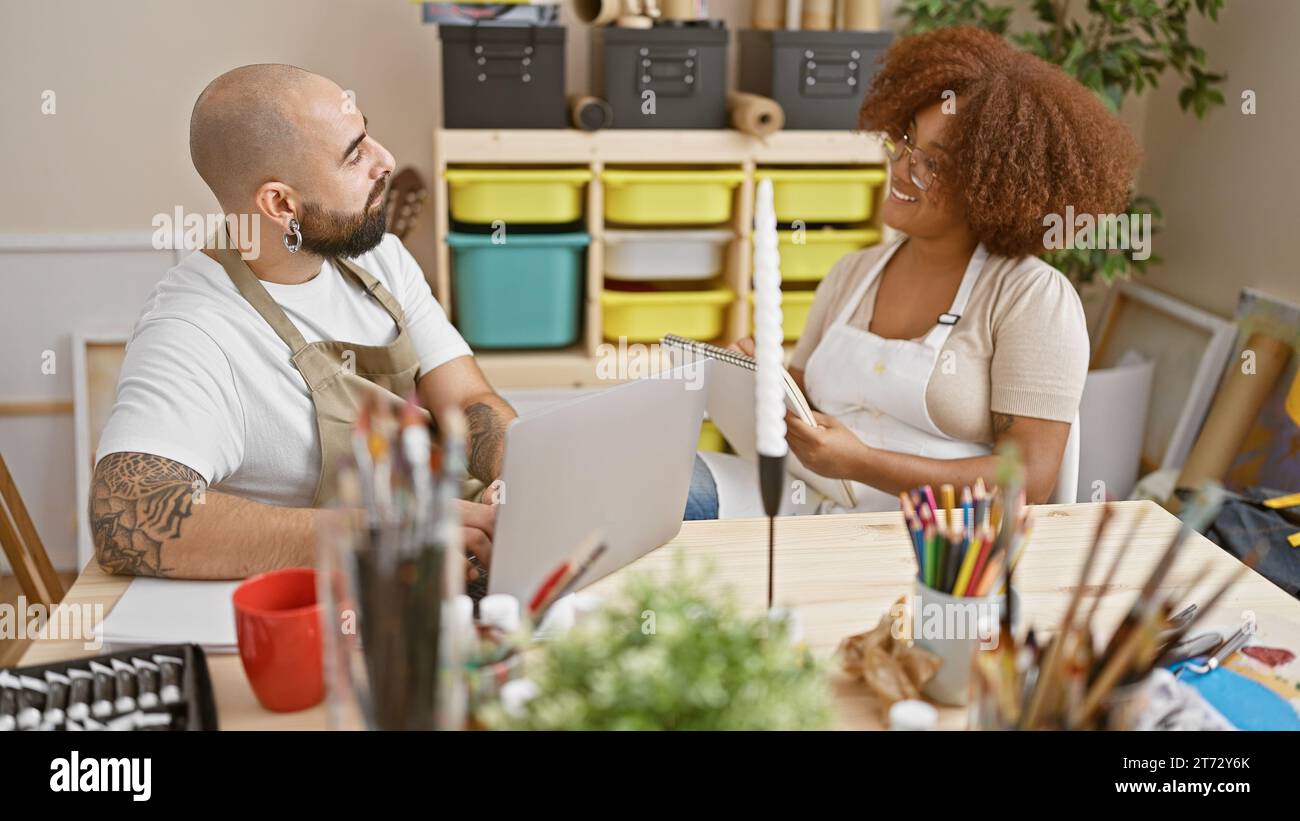 Two smiling artists confidently drawing together on a laptop in their ...