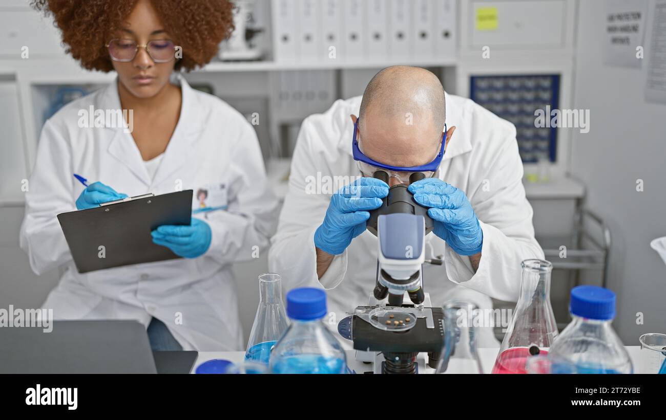 Inside the buzzing lab, two committed scientists, man and woman ...