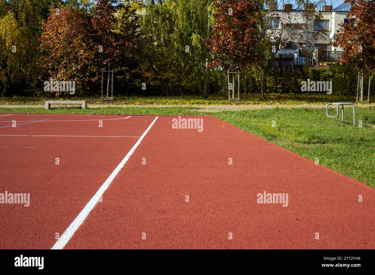 A vibrant red basketball court with a white painted line running across ...