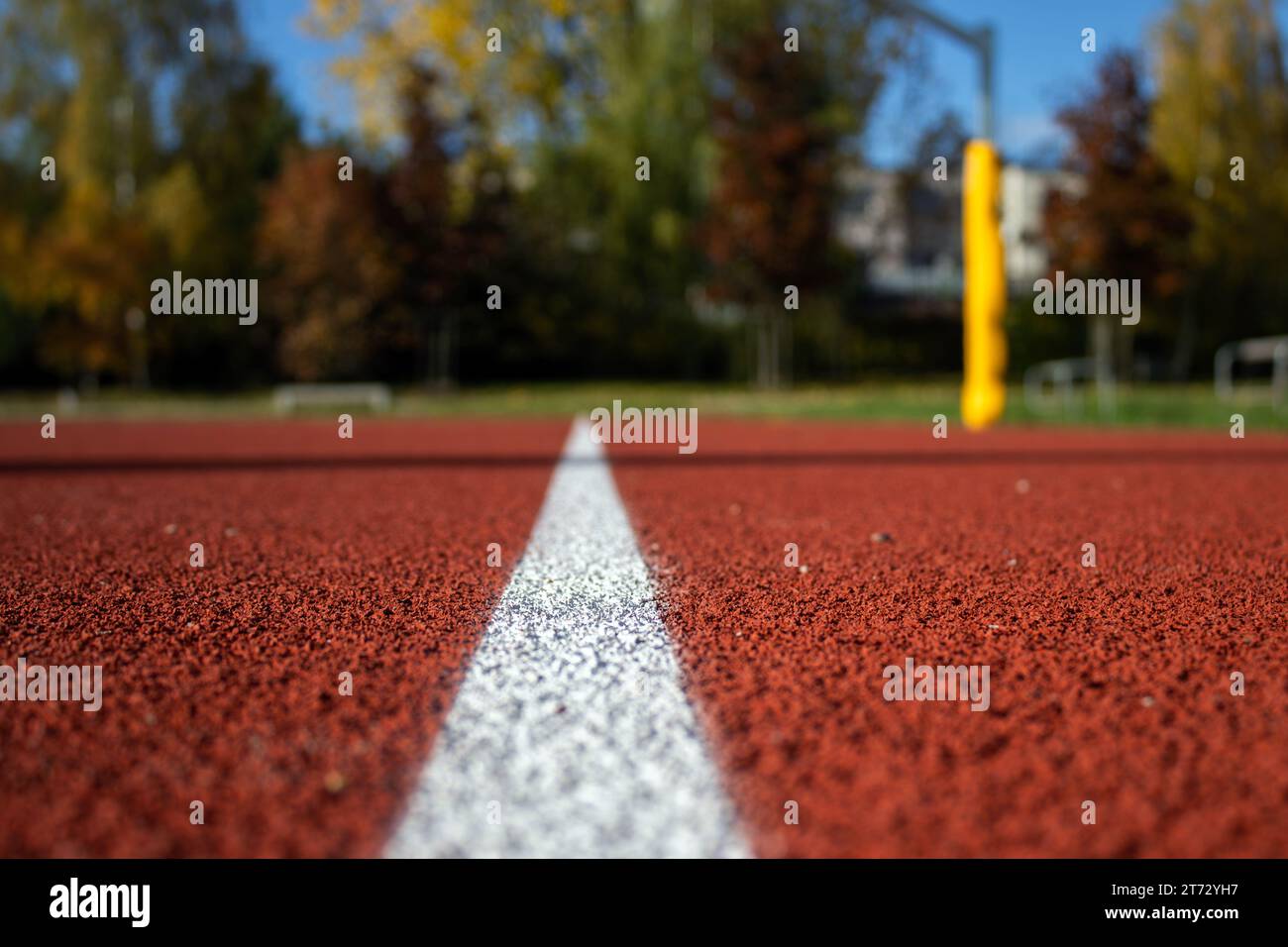 A vibrant red basketball court with a white painted line running across ...