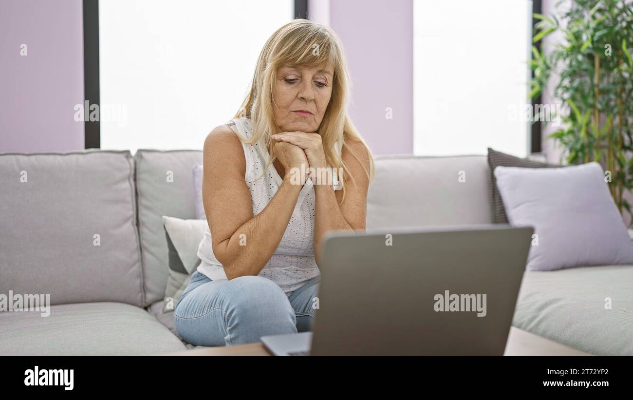 In her cozy home, a serious and focused middle age blonde woman is ...