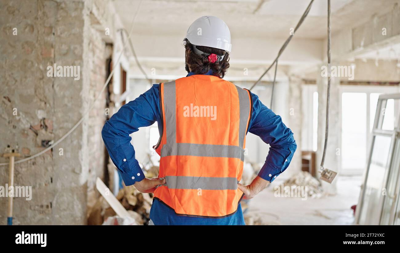 Young hispanic man architect standing backwards at construction site ...