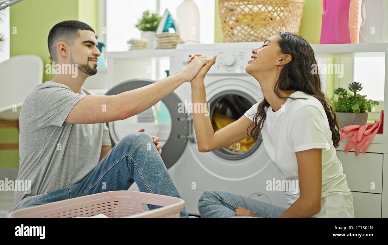 High-five for housework! beautiful couple celebrating love and laundry ...