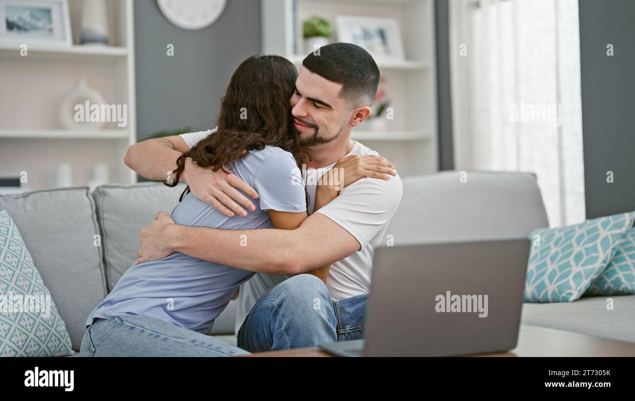Beautiful couple, deeply in love, hugging and smiling, using a laptop ...