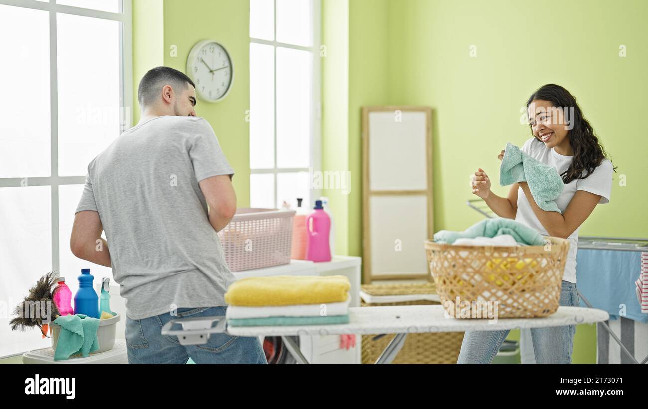 Beautiful couple playfully throwing clothes during a laundry battle in ...