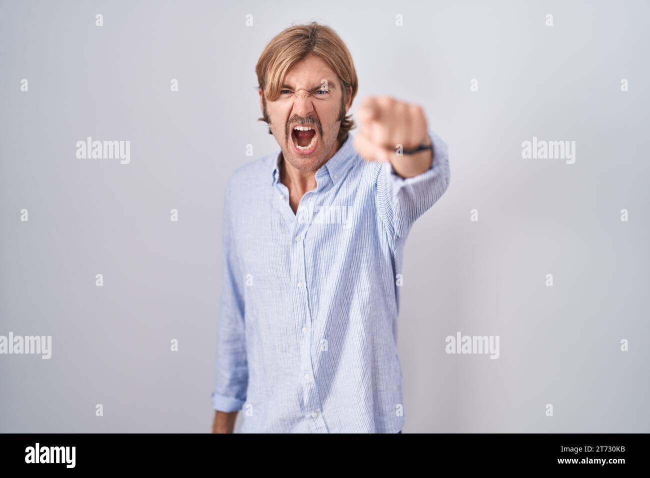 Caucasian man with mustache standing over white background pointing ...